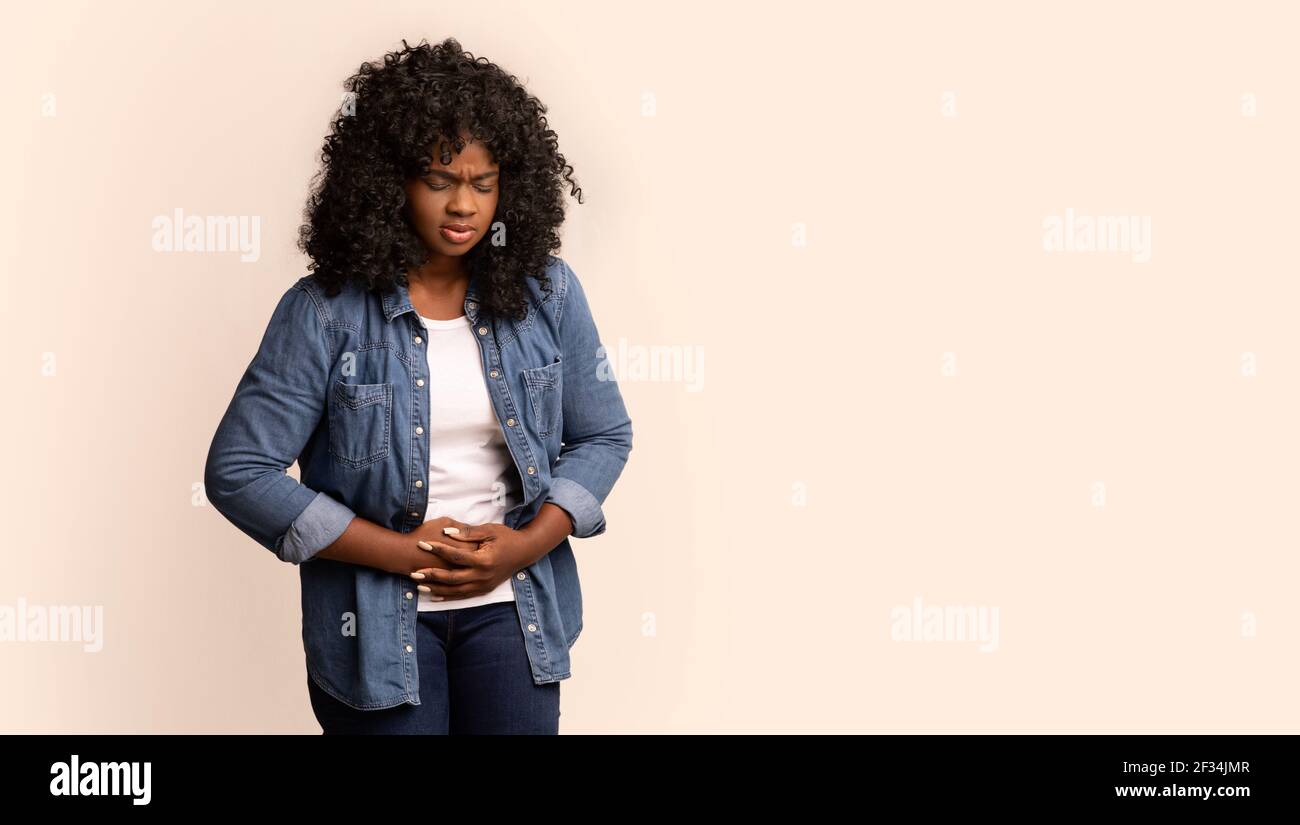 Sad black lady touching her belly on grey background Stock Photo - Alamy