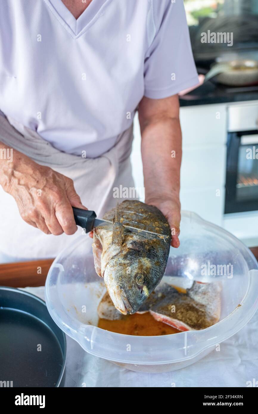 Fish being seasoned and cut by a knife to be ready for cooking Stock ...