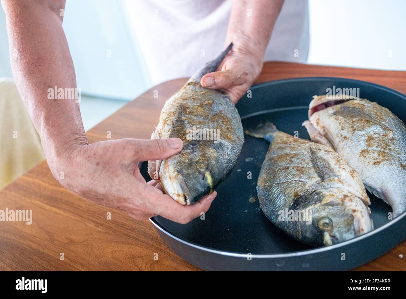 Pouring sauce on fishes before going to the oven Stock Photo - Alamy