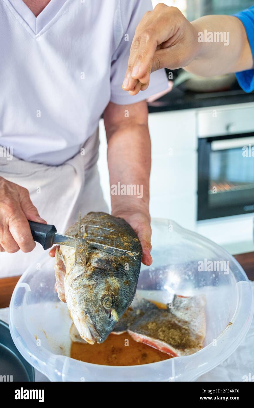 Fish being seasoned and cut by a knife to be ready for cooking Stock ...