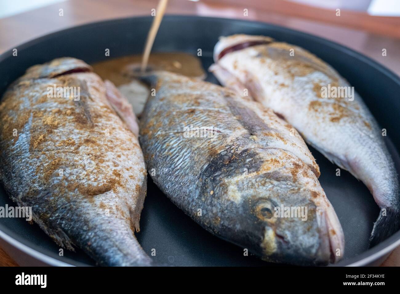 Pouring sauce on fishes before going to the oven Stock Photo - Alamy