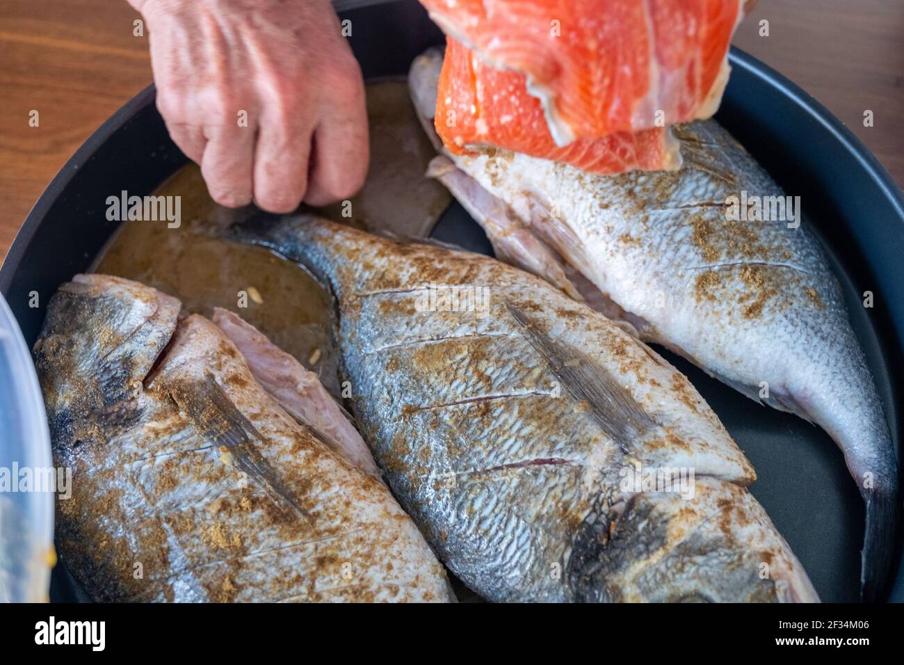 Pouring sauce on fishes before going to the oven Stock Photo - Alamy