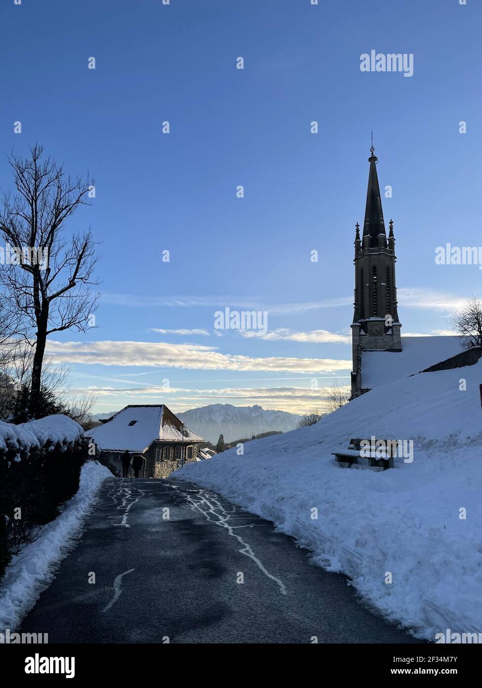 A vertical shot of a narrow road and chapel in snowy Chatel Saint-Denis ...