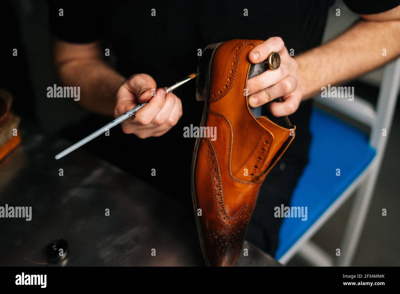Close-up top view of shoemaker painting heel and sole of light brown ...