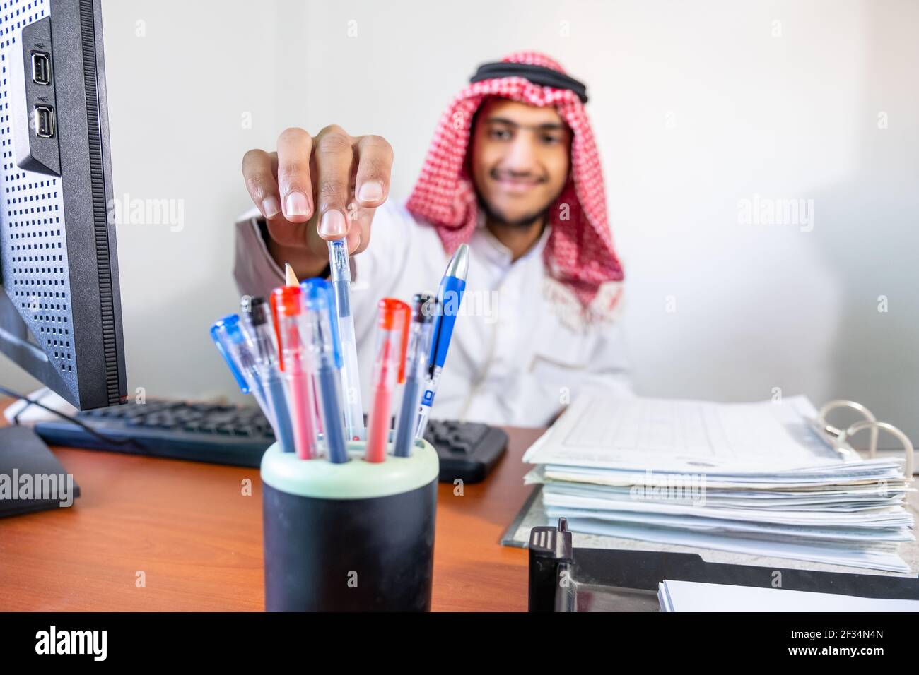 Arabic Muslim employee pulling pen to write with Stock Photo - Alamy