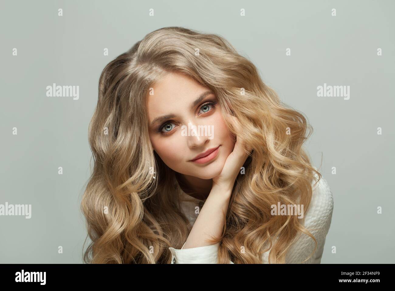 Lovely friendly blonde woman with long perfect hair looking at camera ...