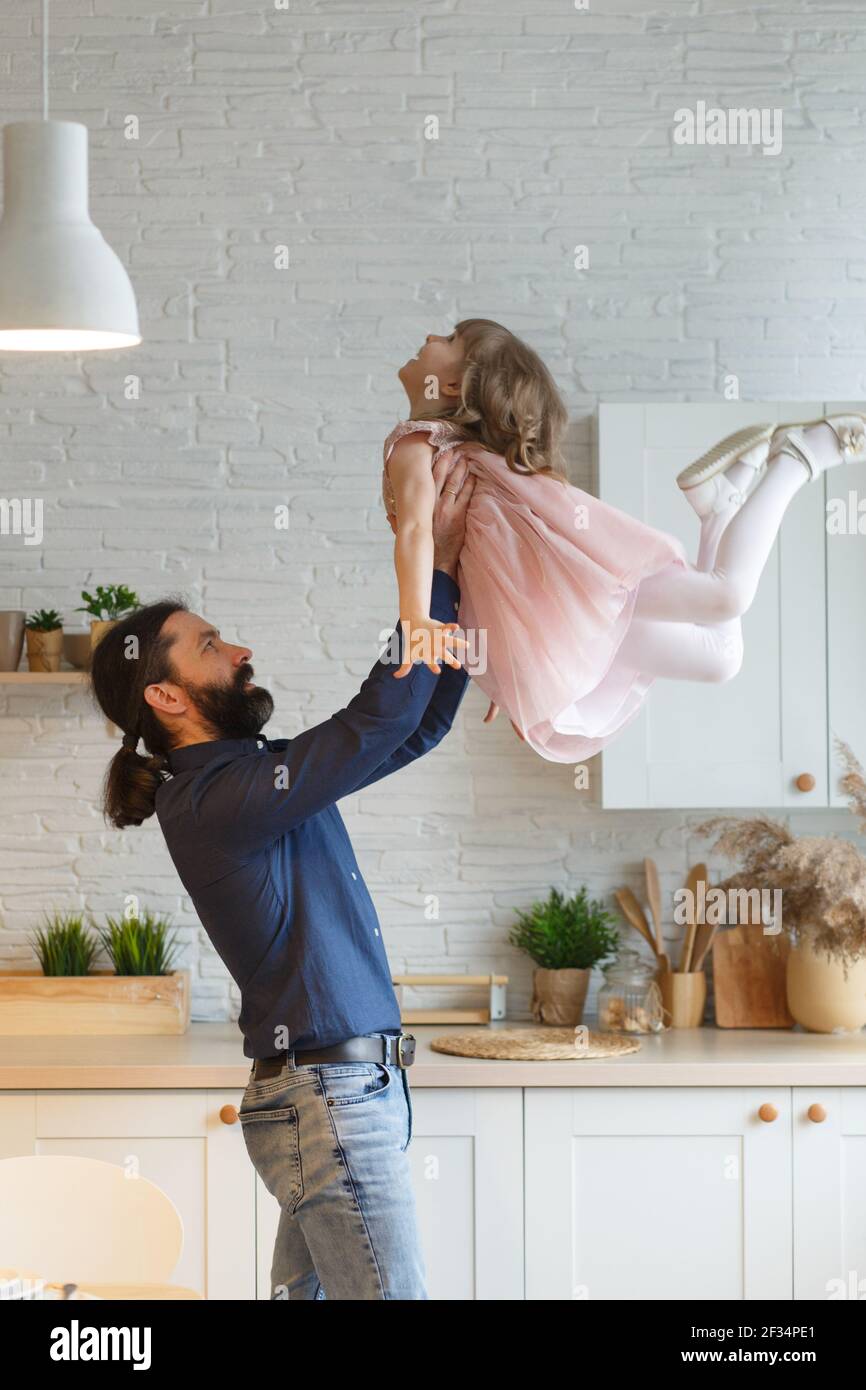 Happy young man lifting small preschool child daughter in air standing ...