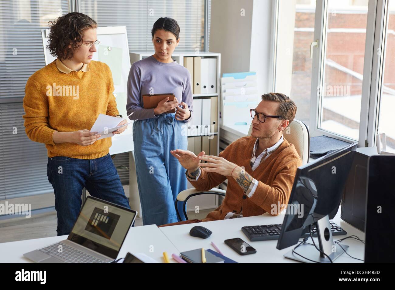 High angle portrait of team leader giving instructions to colleagues ...