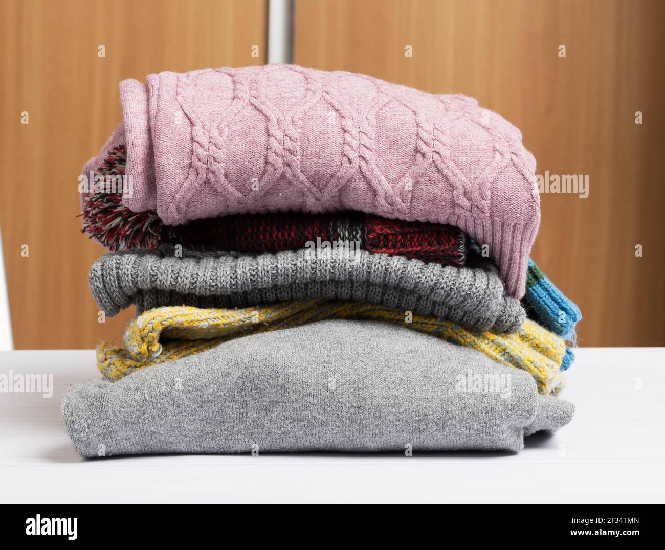 stack of clean folded clothes on white table, help and volunteering ...