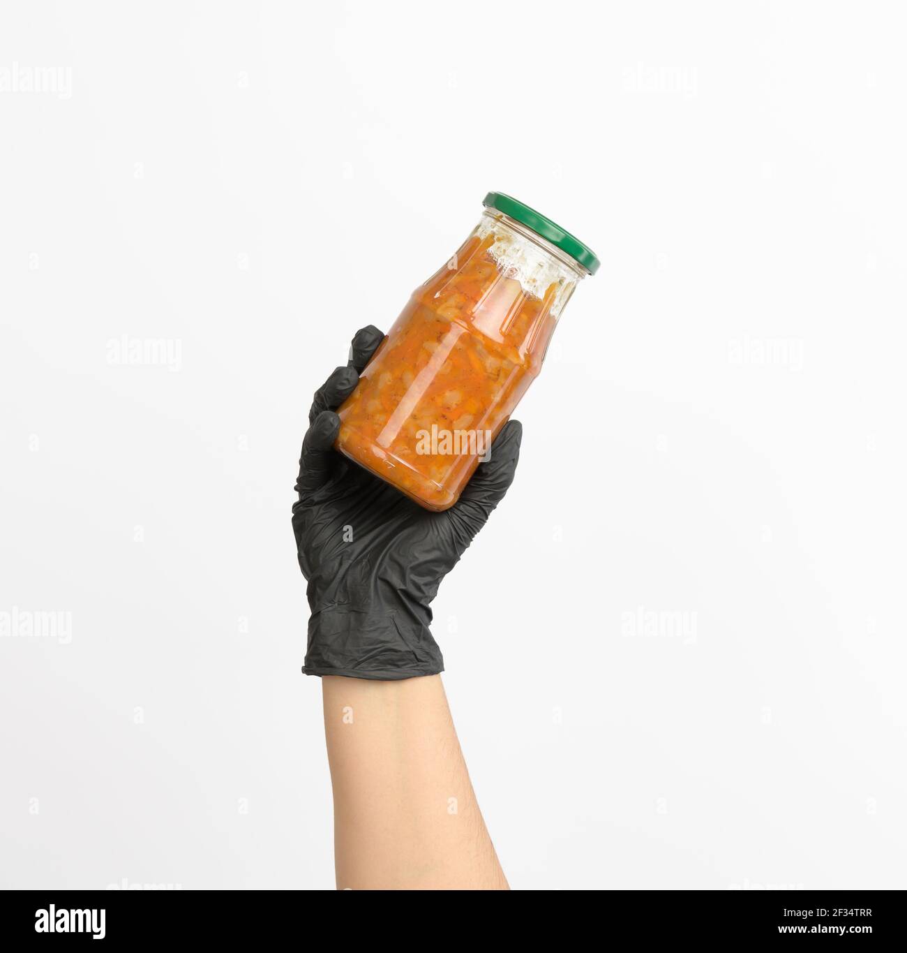female hand in a black glove holds a glass jar with cooked beans in ...