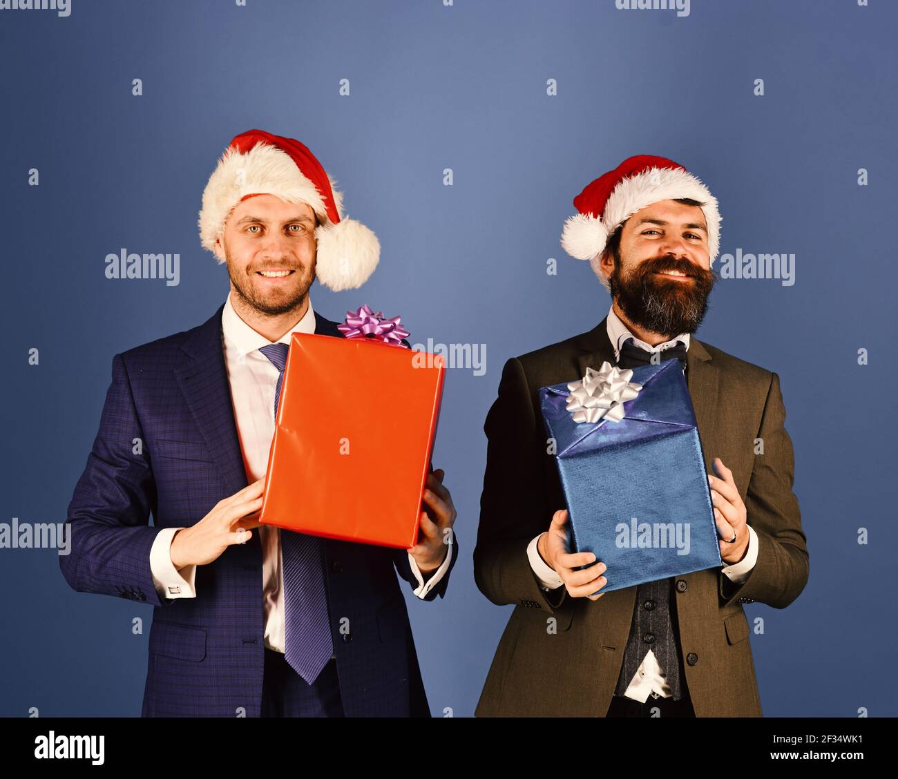 Men in smart suits and Santa hats on blue background Stock Photo - Alamy