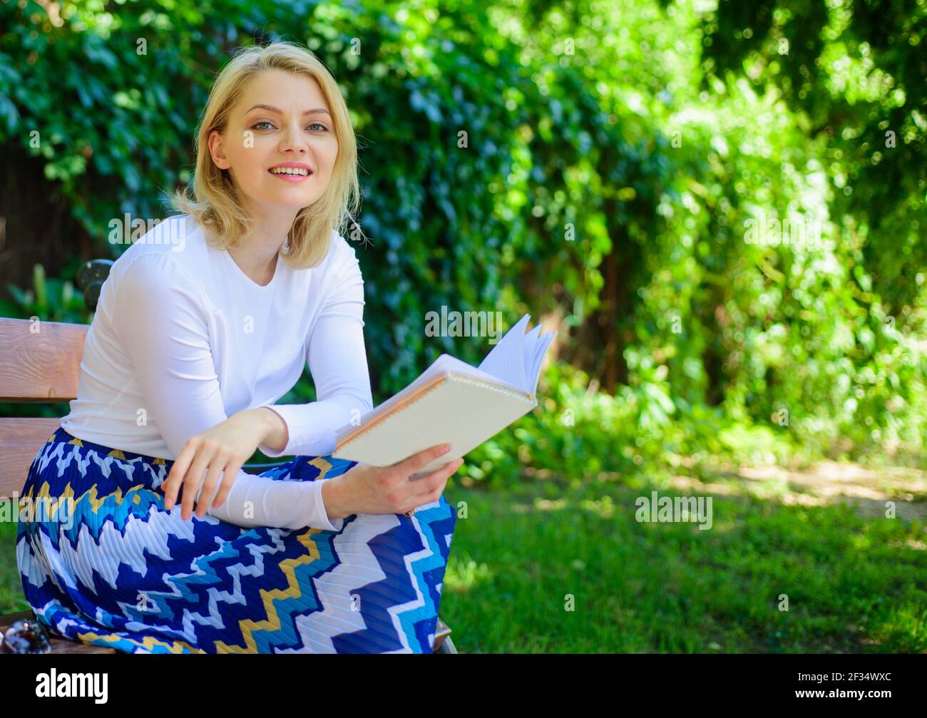 Woman happy smiling blonde take break relaxing in garden reading poetry ...