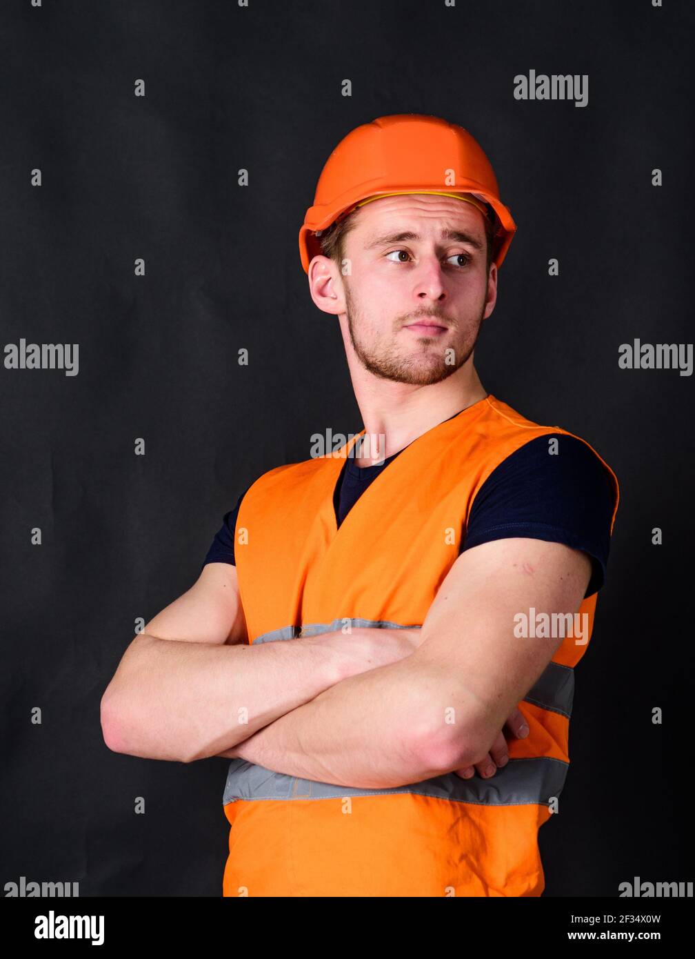 Man in helmet, hard hat hold arms crossed on chest, black background ...