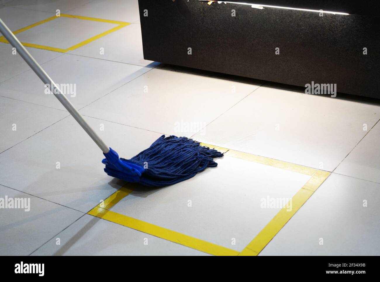 wiping a floor with yellow stripes, using a blue mop Stock Photo - Alamy