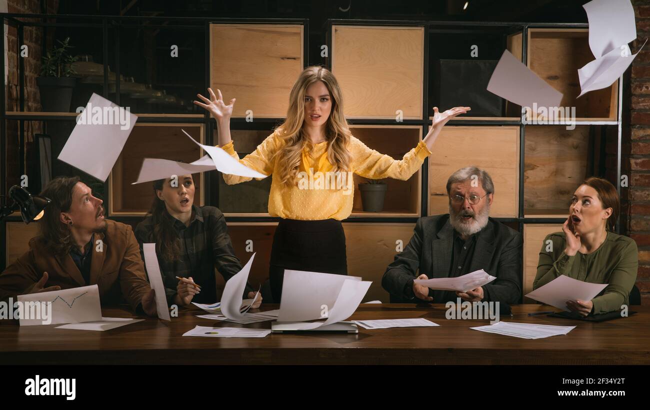 Flying sheets. Young colleagues working together in a office styled ...