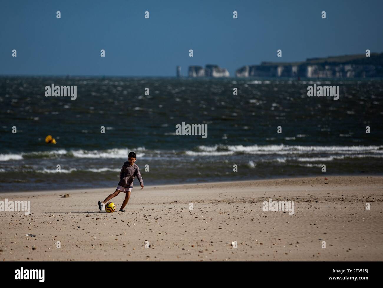 A young boy playing football on Sandbanks beach in Dorset Stock Photo ...