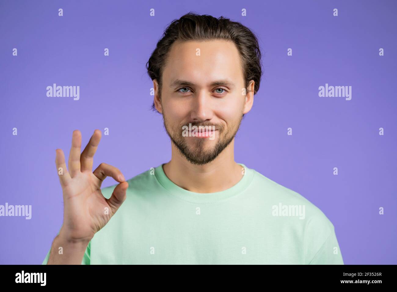 Handsome man shows okay, ok gesture. Happy guy on violet background ...