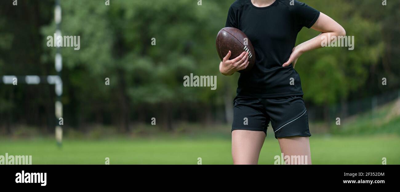Girl holds a rugby ball, isolated on a green background. Woman sport ...
