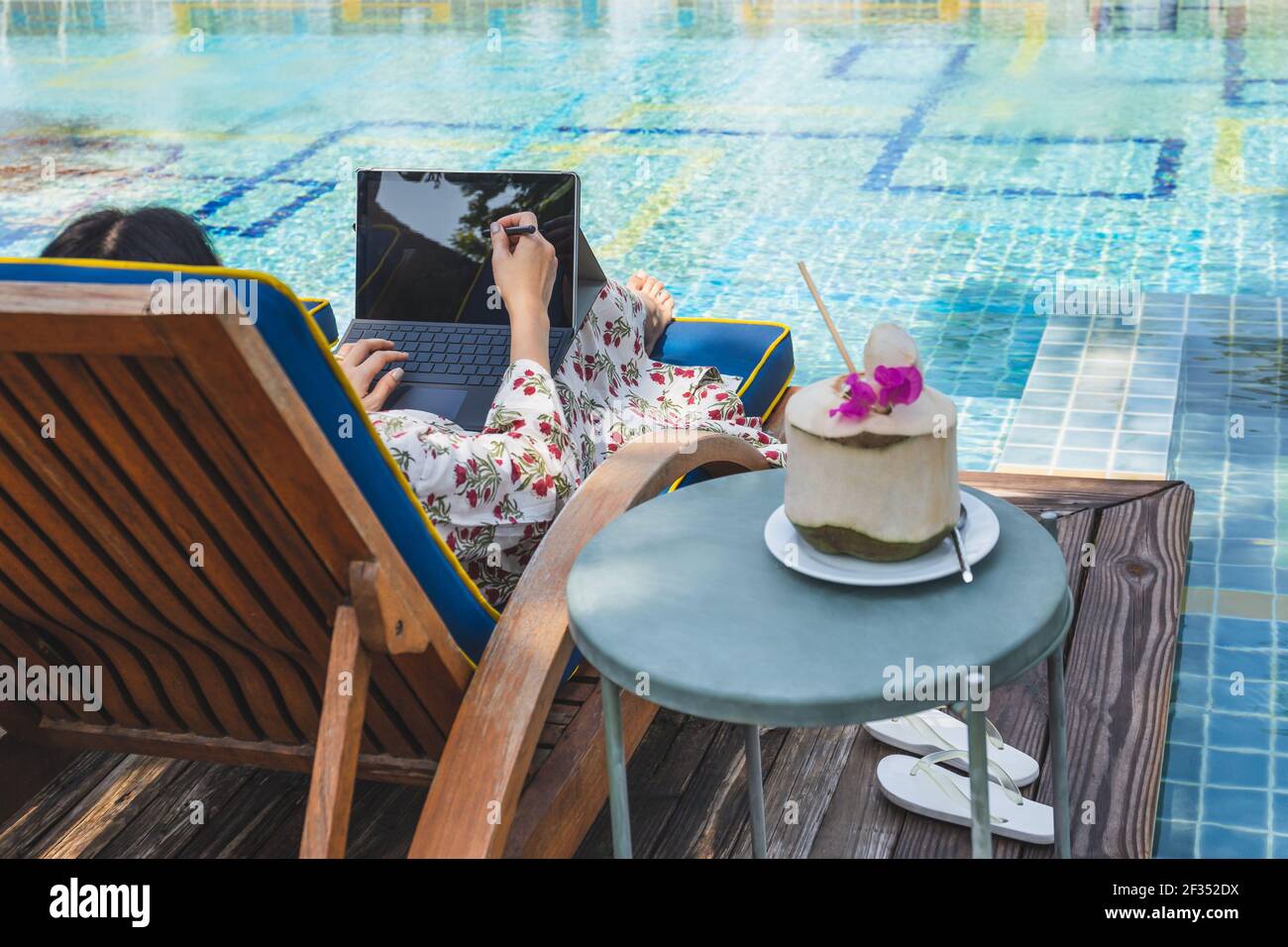 Woman using laptop computer by the swimming pool Stock Photo - Alamy
