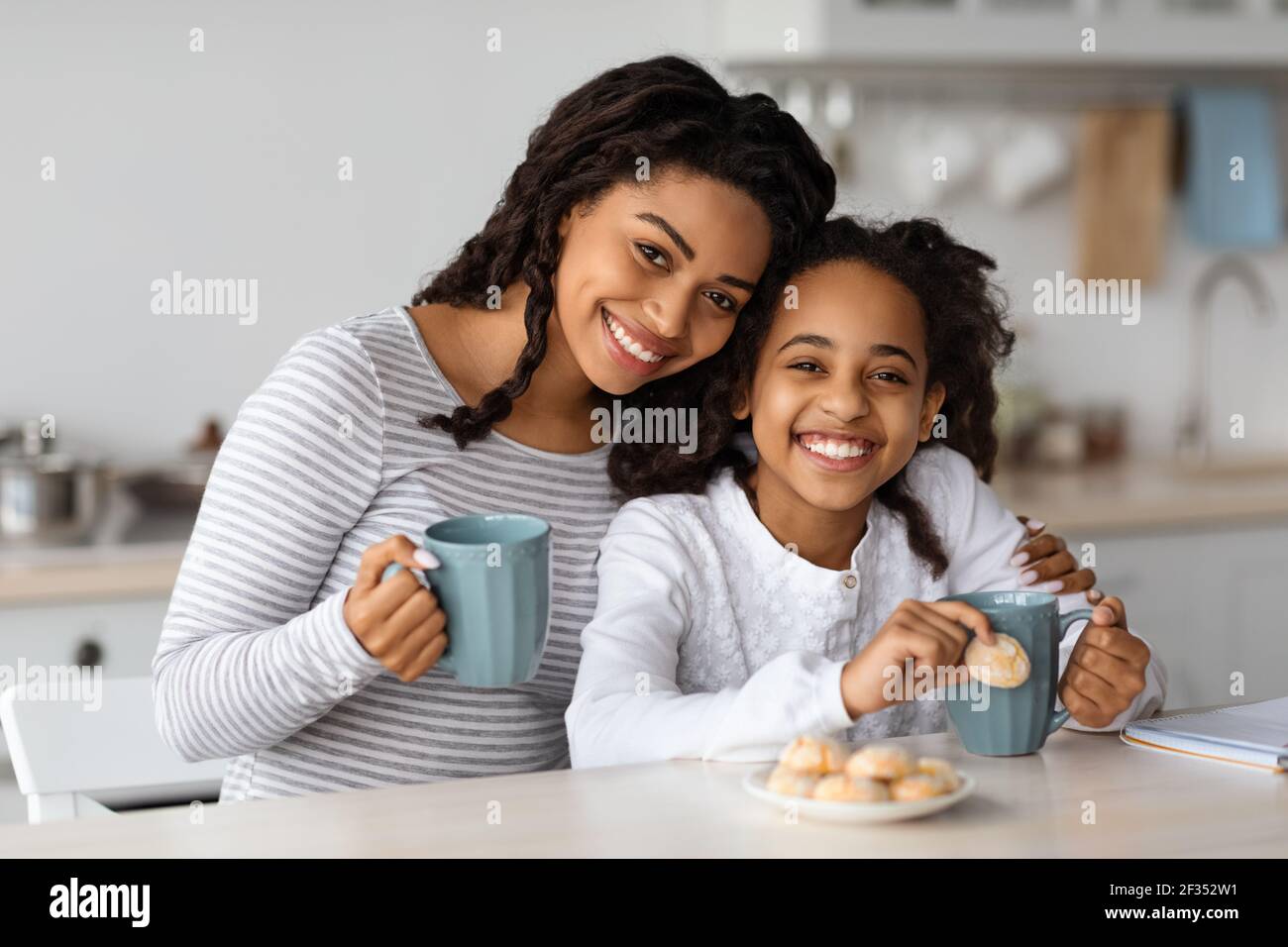 Cute black mother and daughter drinking tea with cookies Stock Photo ...