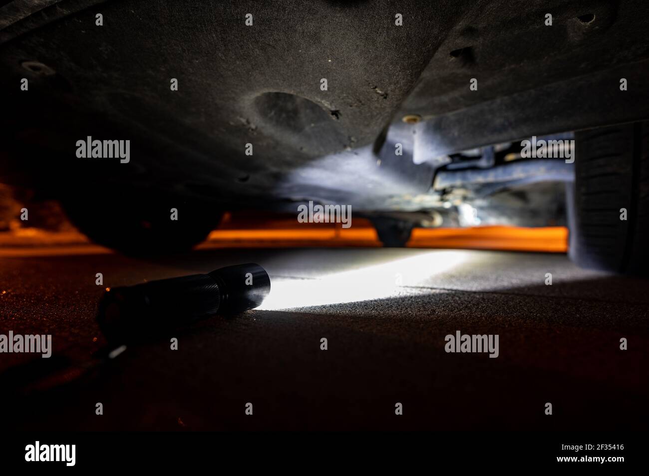 Using a flashlight to look for vehicle problems underneath the hood ...