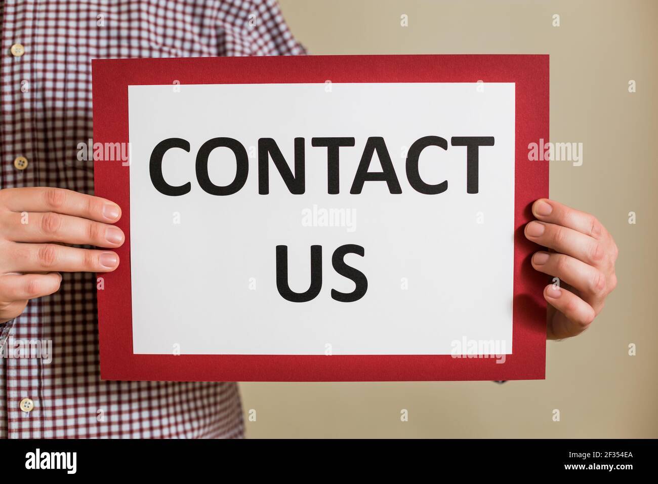 Image of man holding paper with text contact us Stock Photo - Alamy