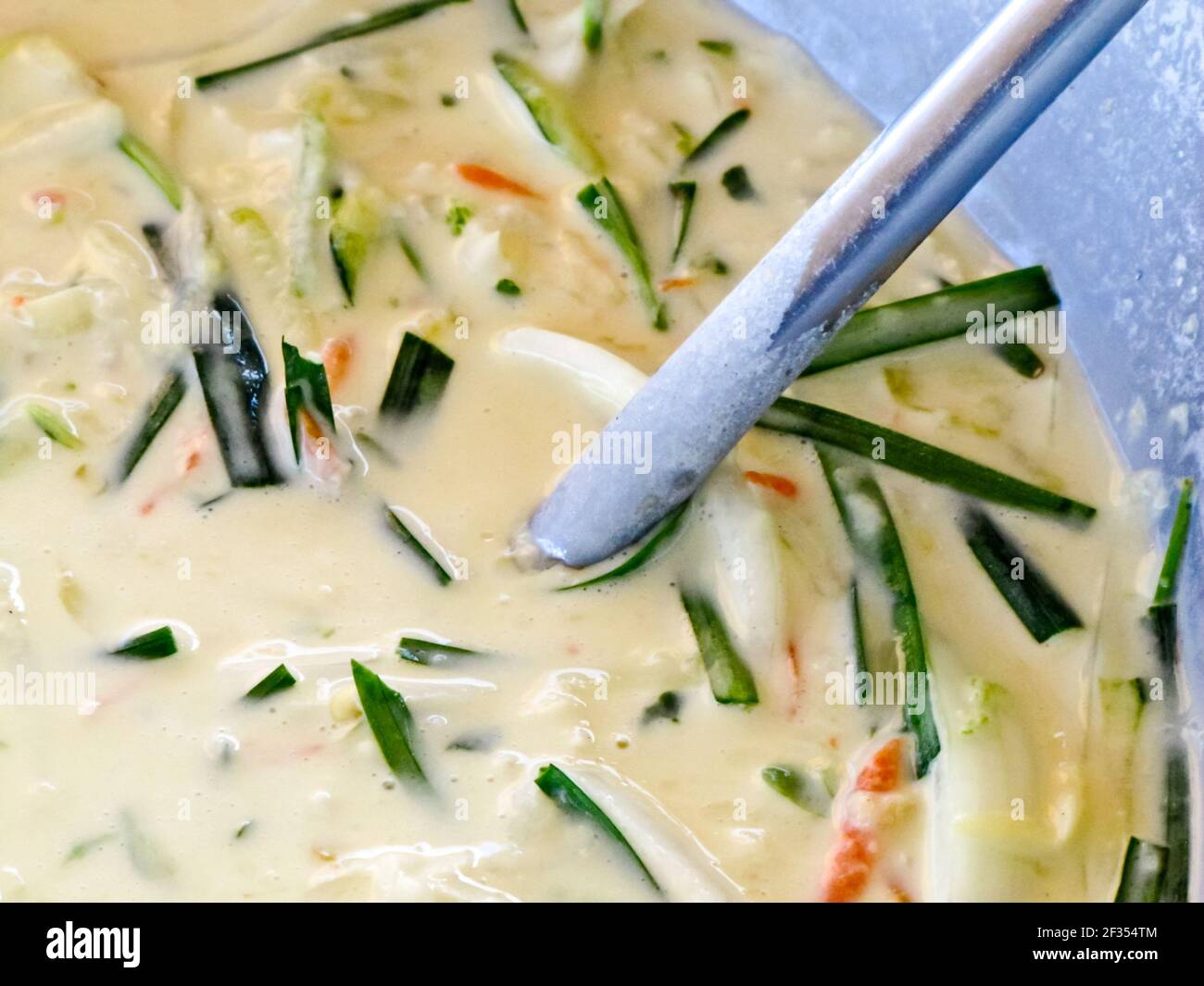 Overhead view of a stainless steel mixing bowl and ladle with a ...