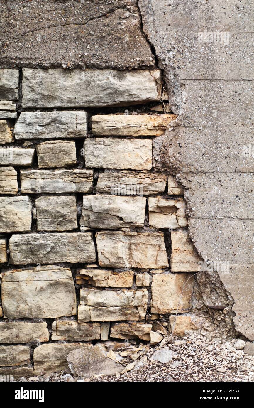 Vertical straight on view of an old worn concrete and stonework wall ...