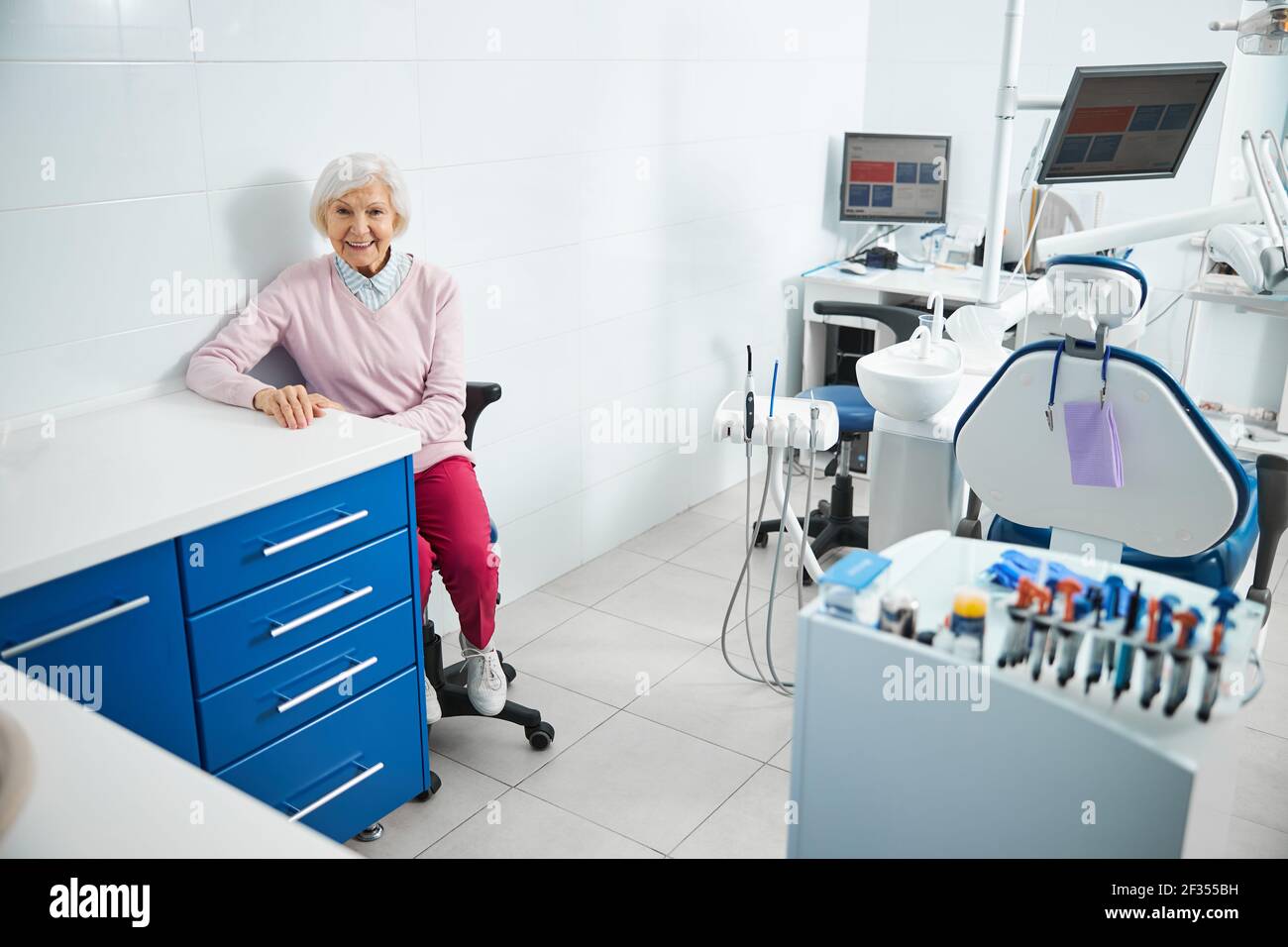Retiring female sitting on an office chair among dental equipment Stock ...