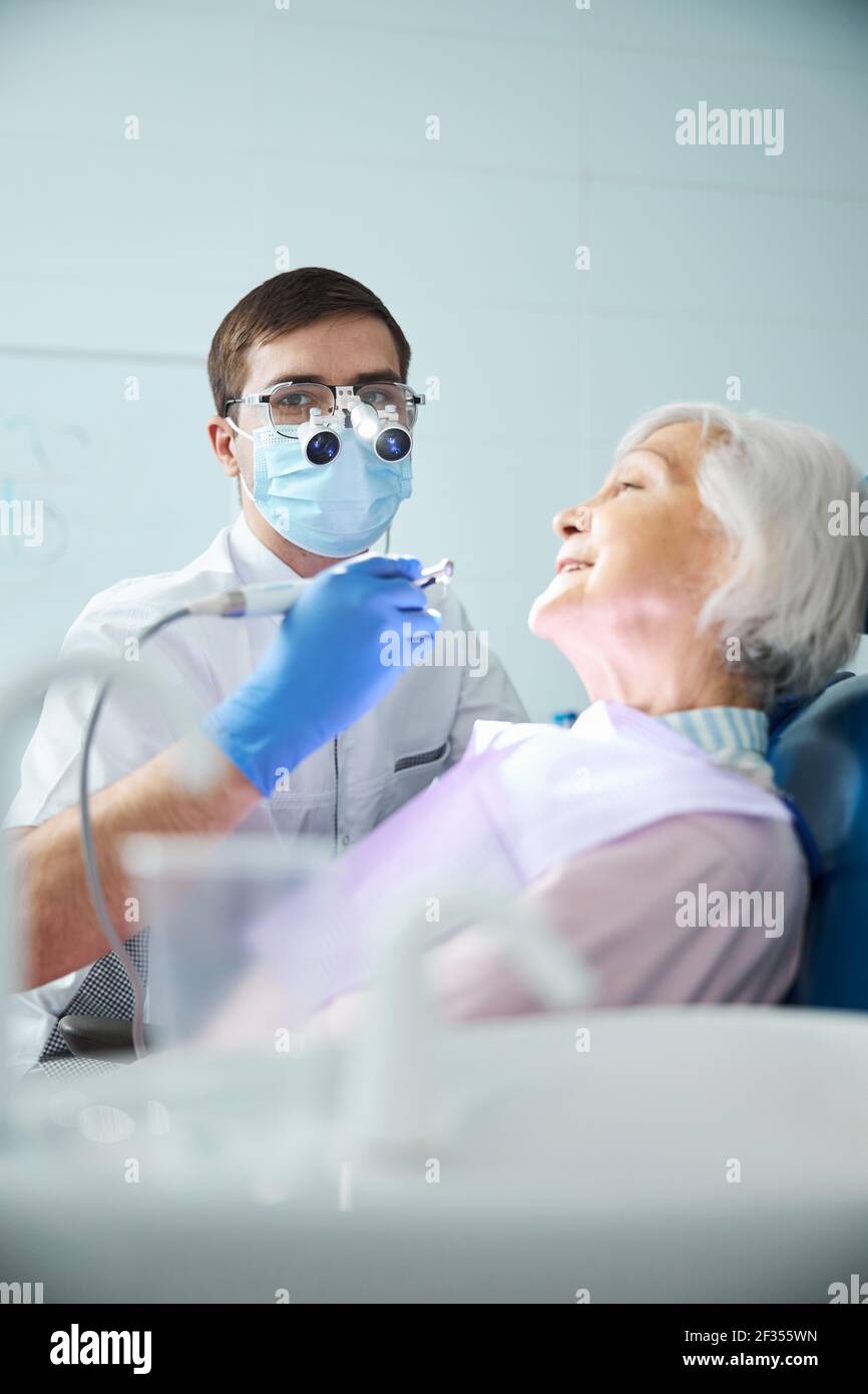 Qualified doctor looking to camera with drill near pleased lady Stock ...