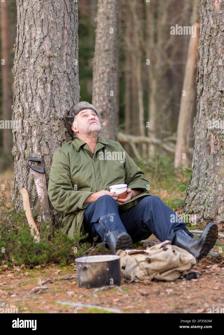 a forester in the forest drinks tea at rest, blurred forest background ...
