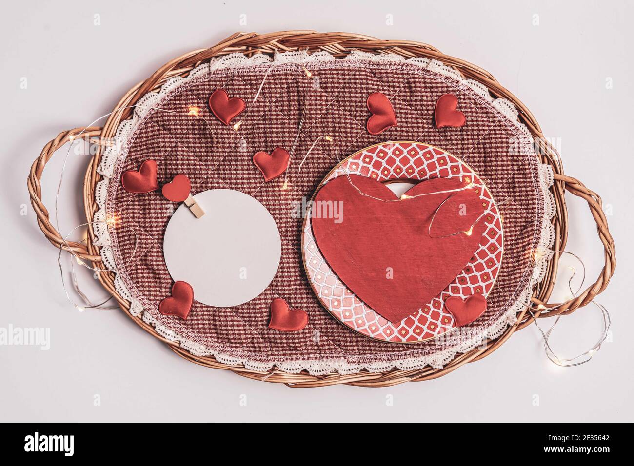 Red heart shaped object placed in a straw salver and round white empty ...