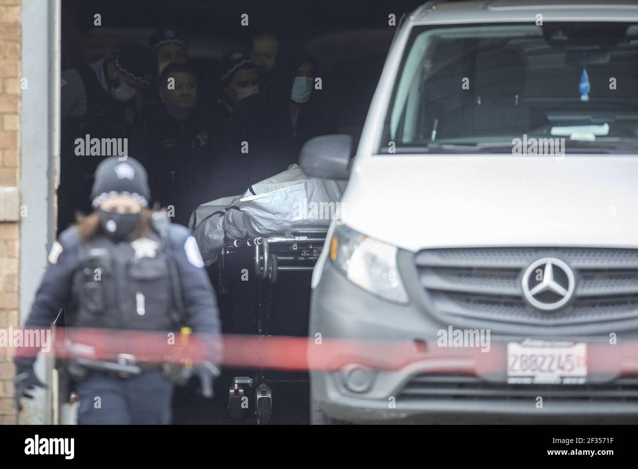 Workers remove the body of a deceased victim as Chicago police officers ...