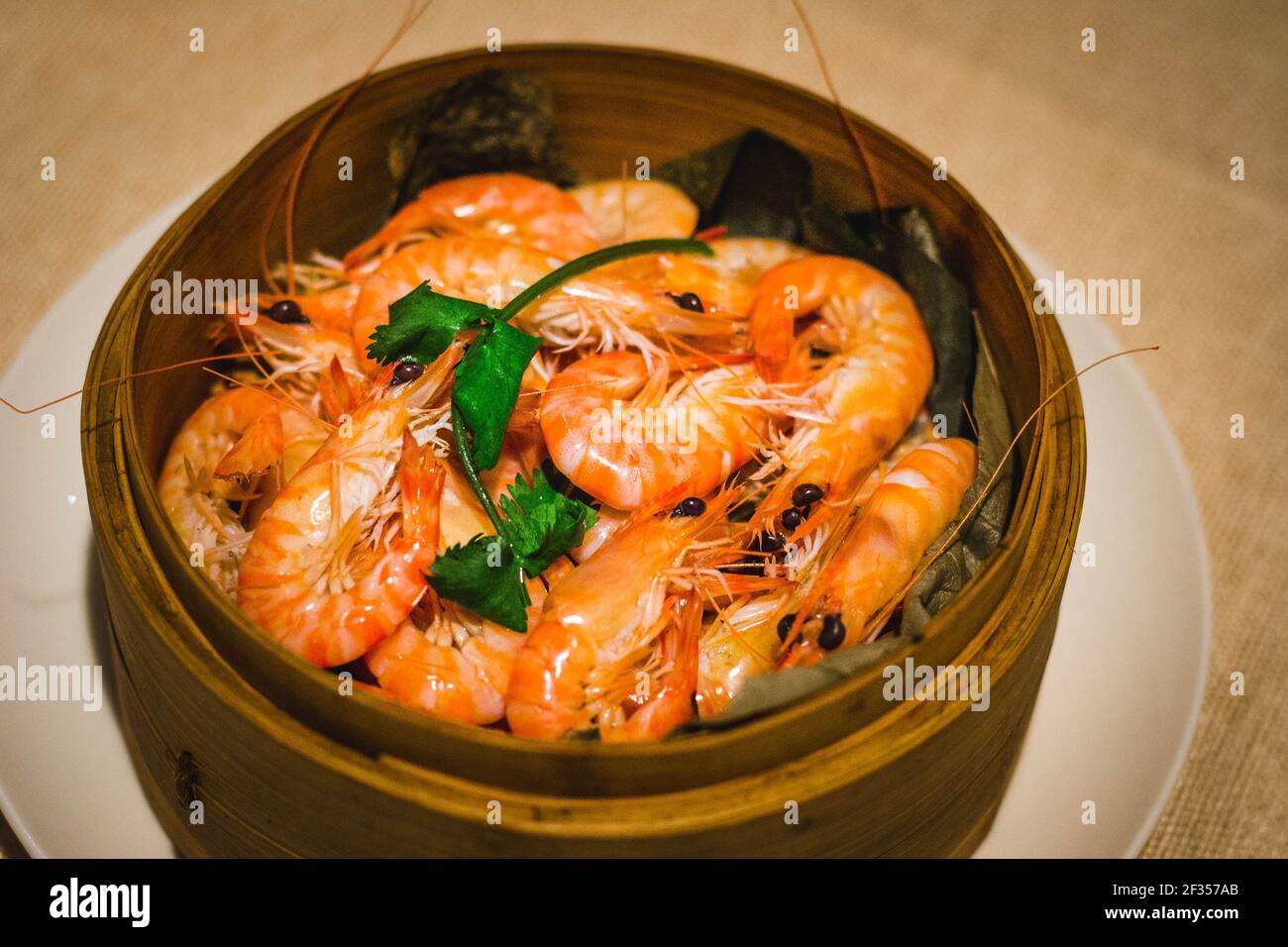 a steam basket with with steamed river prawns and garnished with ...