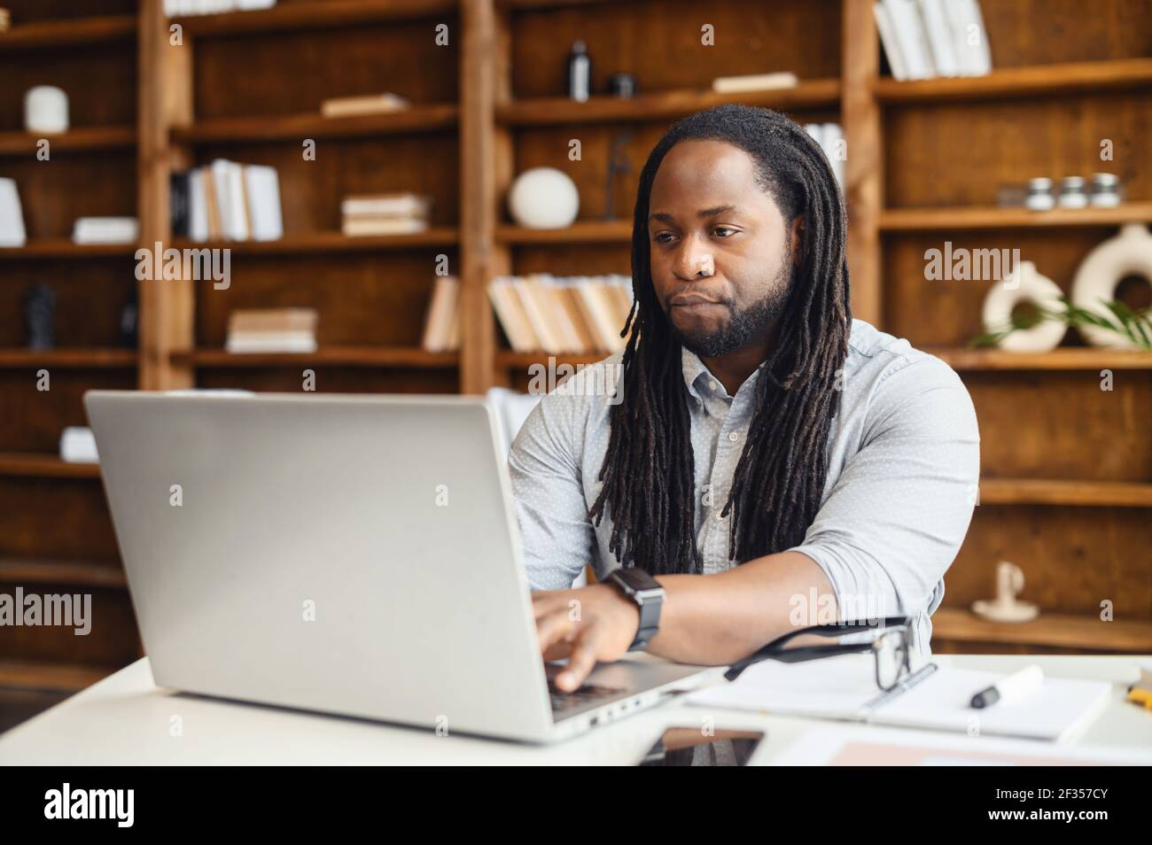 Busy young African-American male office worker with dreadlocks removed ...