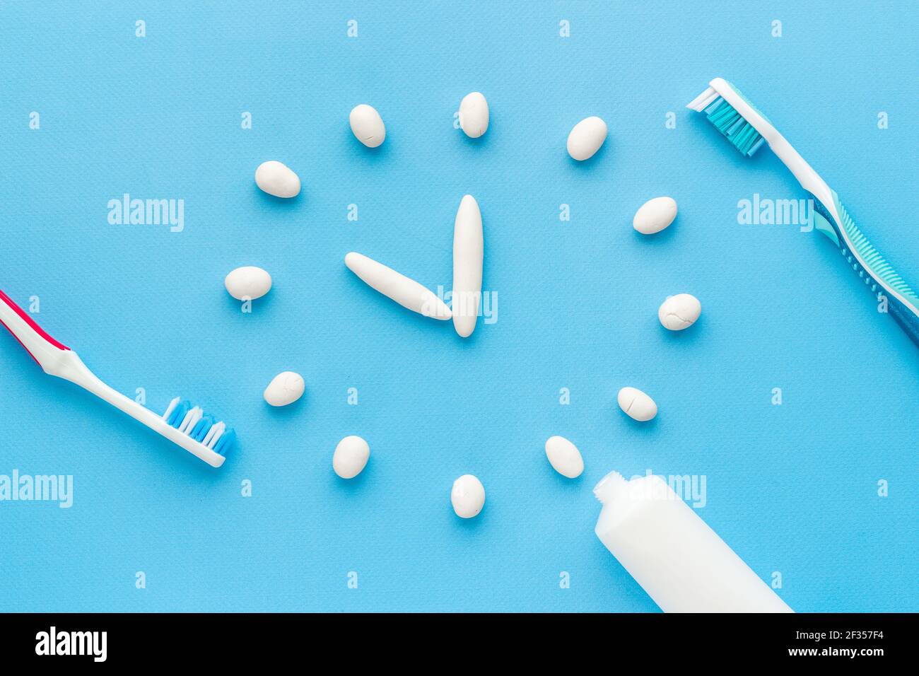 Morning routine concept. Clock made of toothpaste with toothbrushes ...