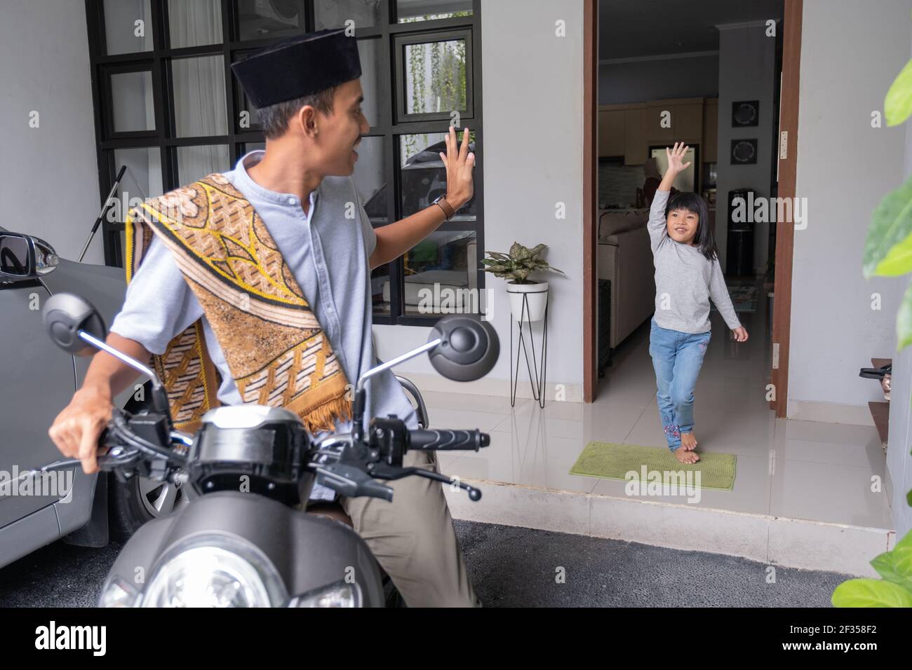 father waving goodbye to his daugther at front house before leaving to ...