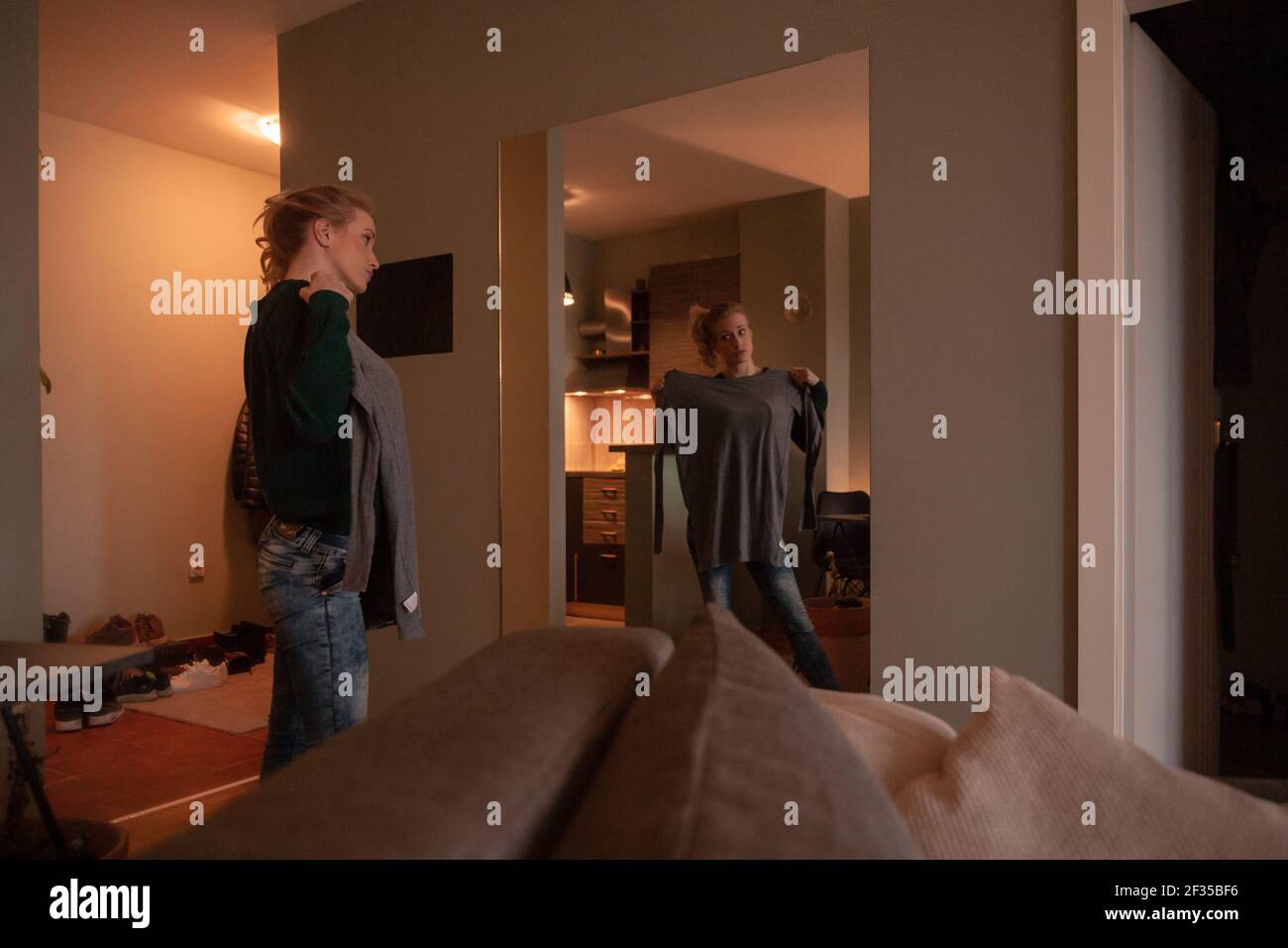 one young woman, looking at herself and trying new clothes in front of ...