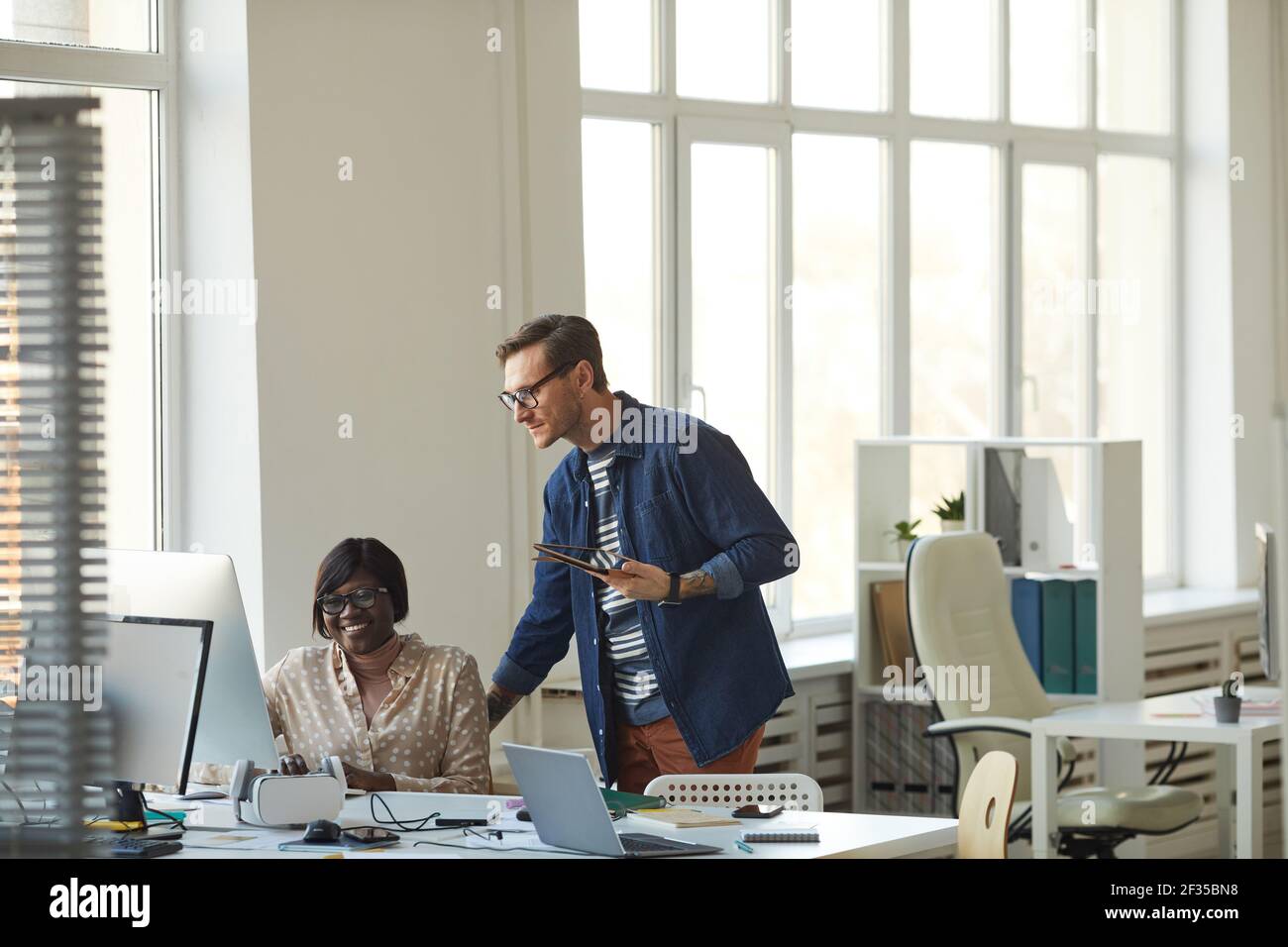 Wide angle view at male manager supervising employee working with ...