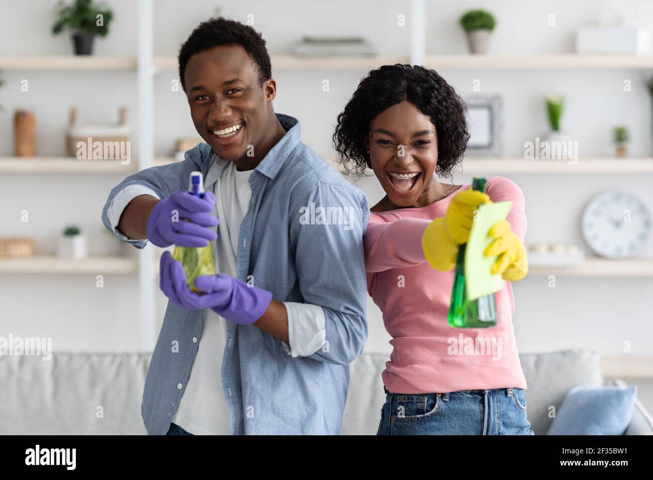 Playful Black Couple Holding Detergents During Cleaning At Home Stock