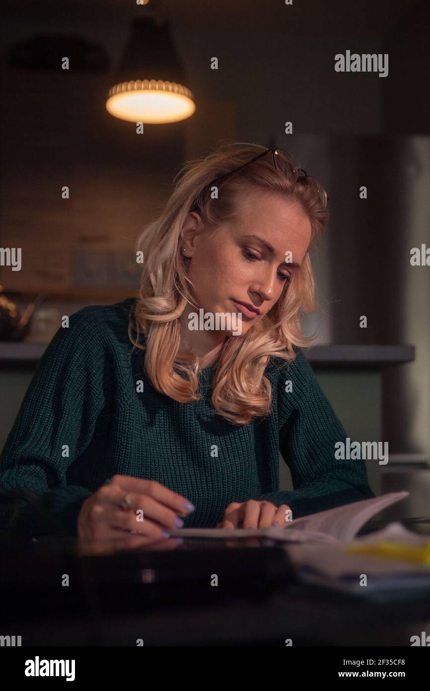 one young woman, reading from a book, late at night at her tome ...