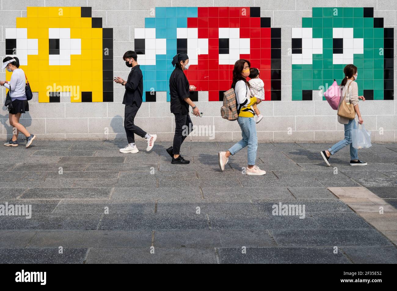 Pedestrians walk past a wall street art depicting the classic arcade ...