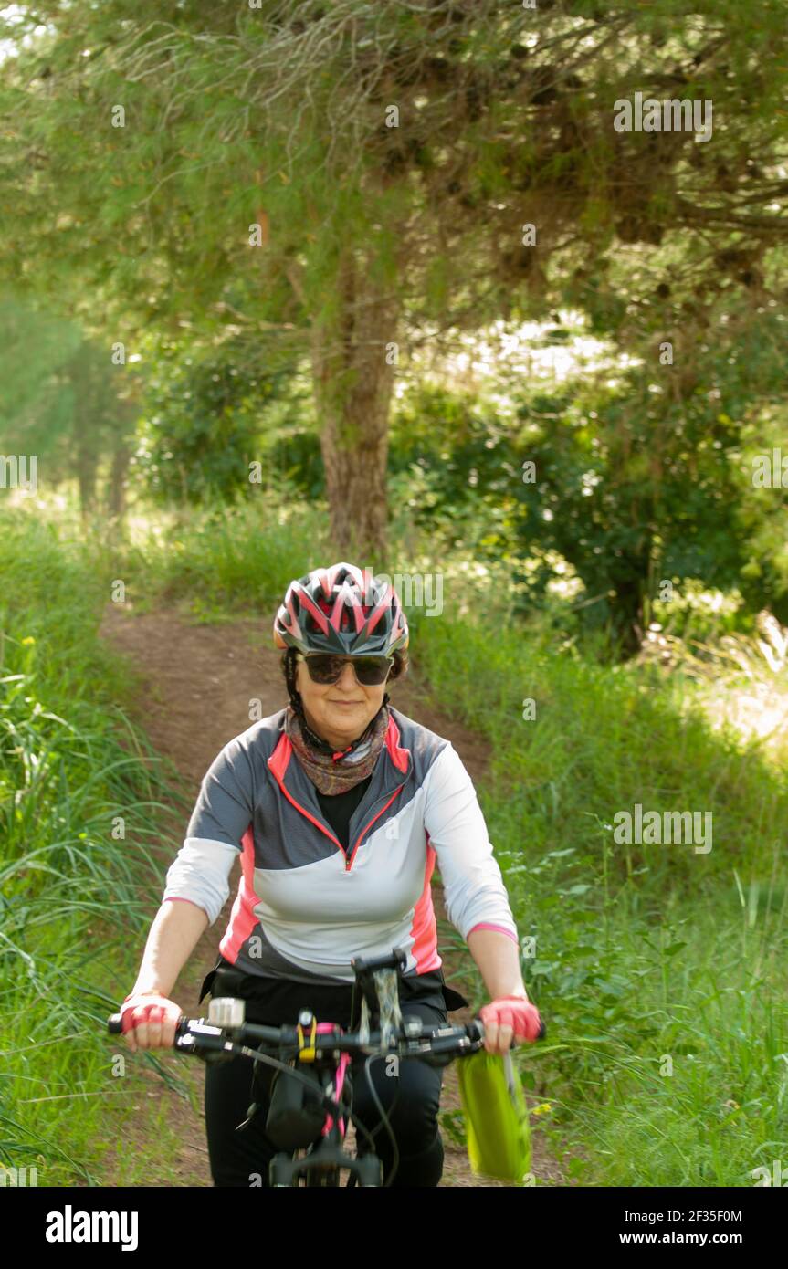female cyclist cycling in nature on a single track path in a forest ...