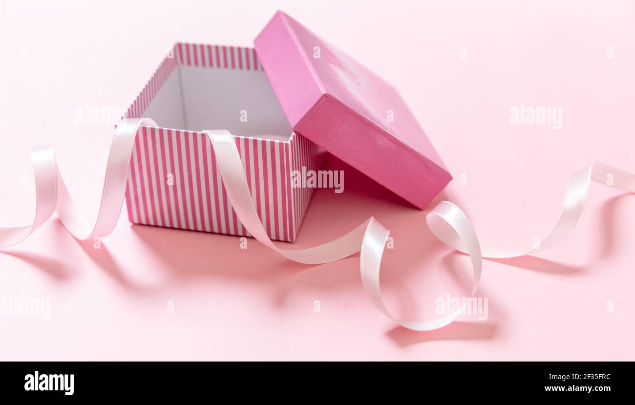 Gift box pink color on pink background. Package open with pink ribbon ...