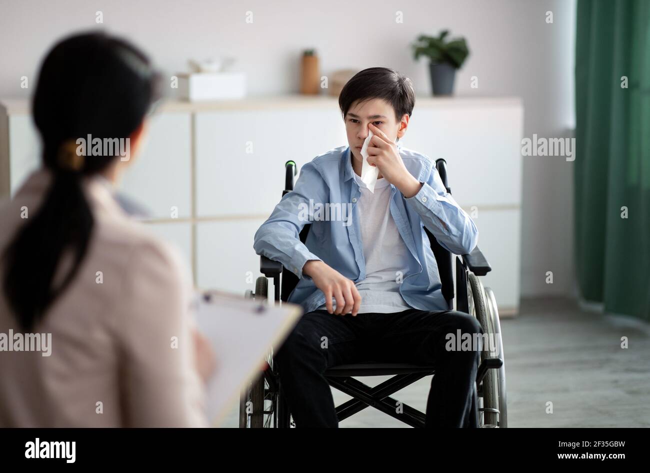 Professional psychologist working with disabled teenager in wheelchair ...