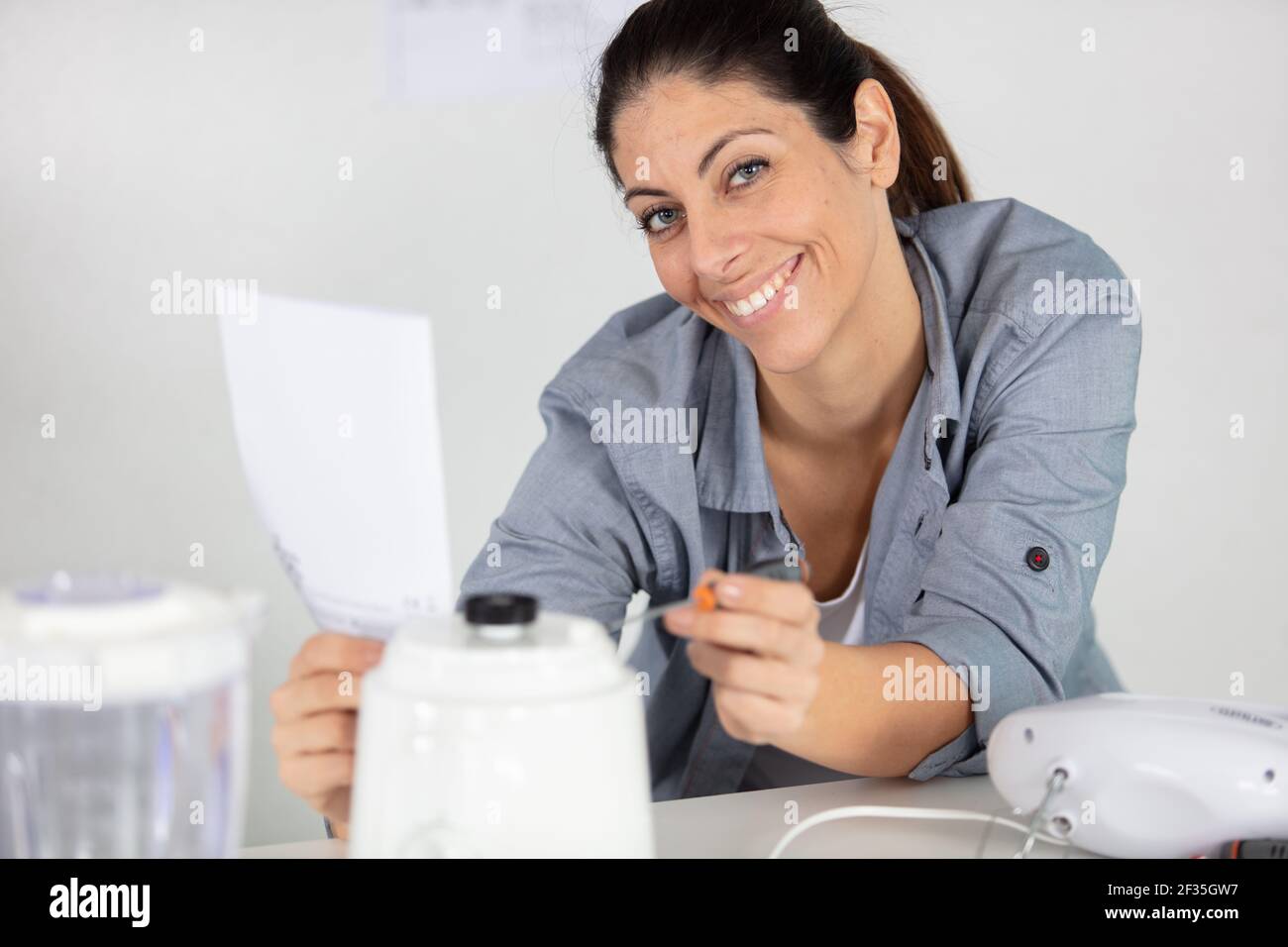 smiling female technician repairing kitchen blender Stock Photo - Alamy