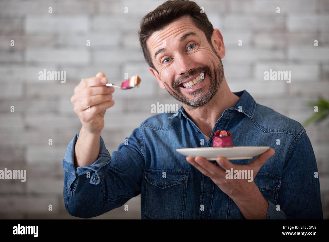funny man is eating a piece of cake Stock Photo - Alamy