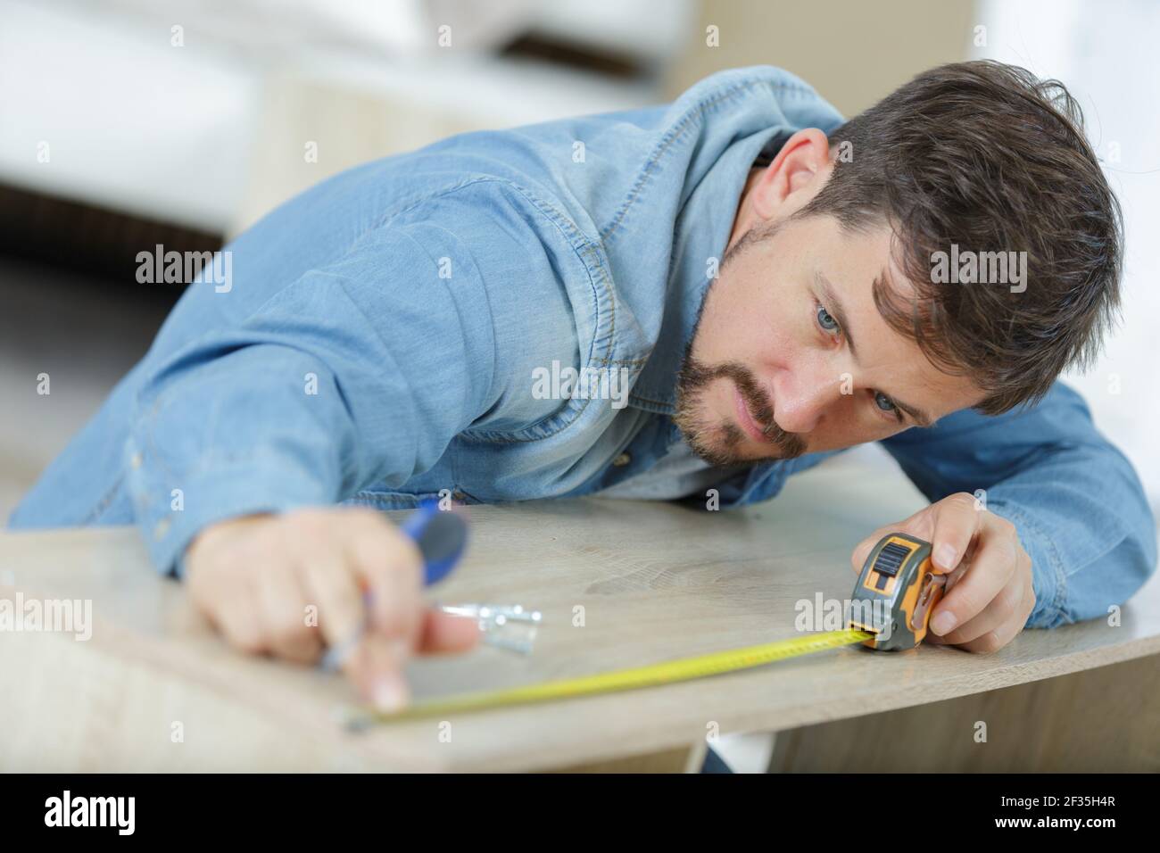 young man using tape measure for measuring a wood board Stock Photo - Alamy