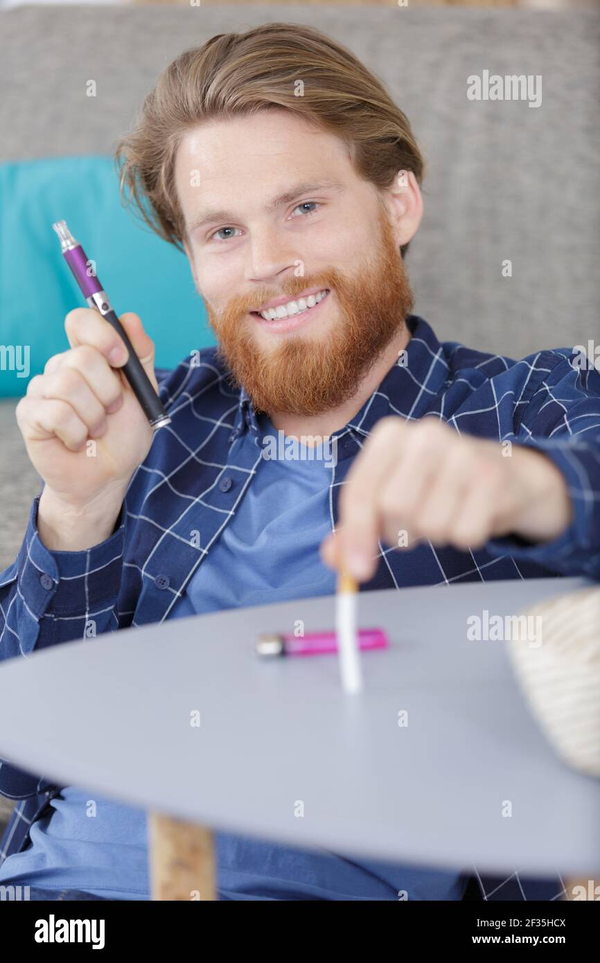 man holding vape and tobacco cigarette over desk Stock Photo - Alamy