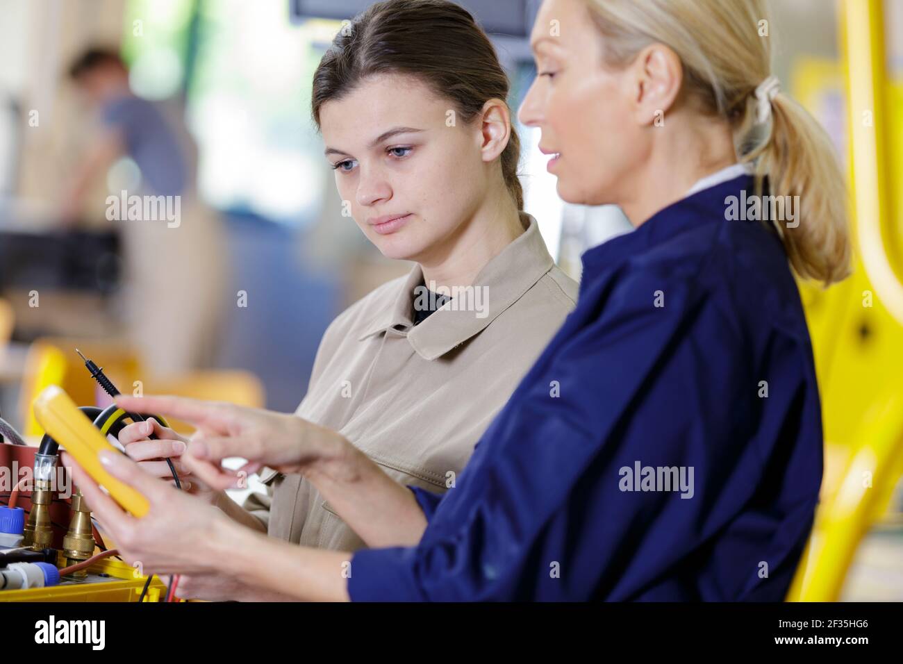 female electrician and apprentice working on checking status equipment ...